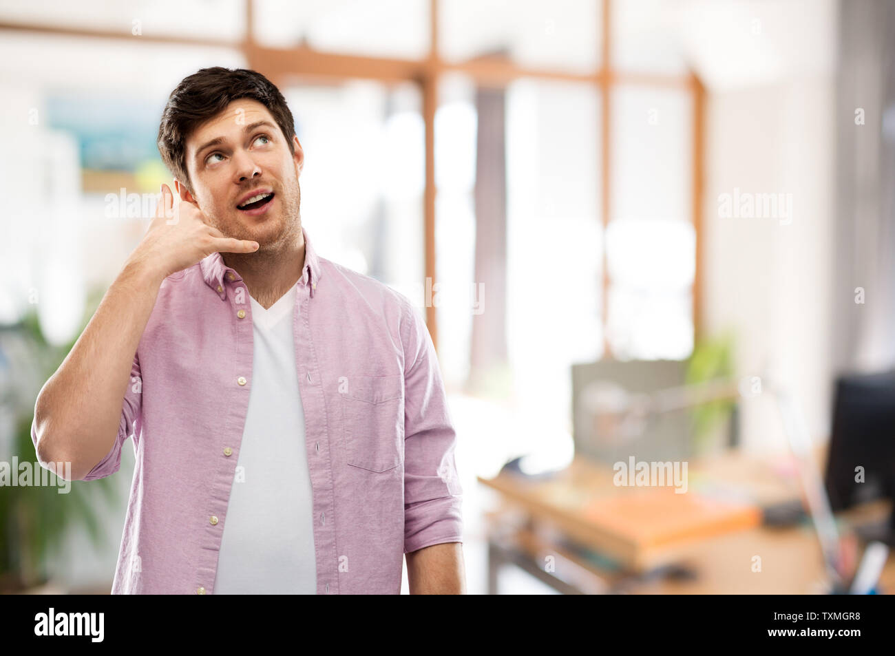 man showing phone call gesture over office room Stock Photo - Alamy