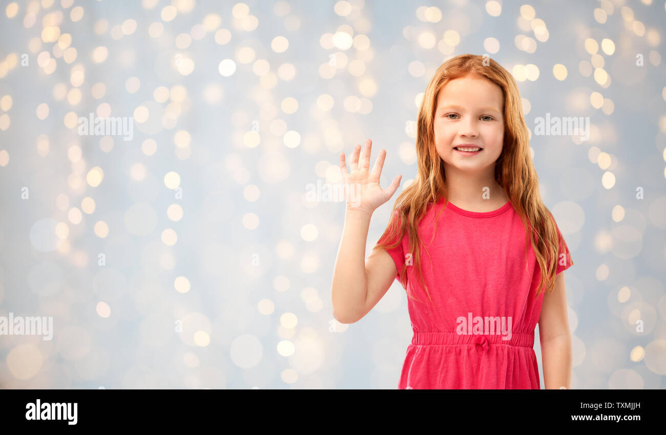 smiling red haired girl waving hand over lights Stock Photo - Alamy
