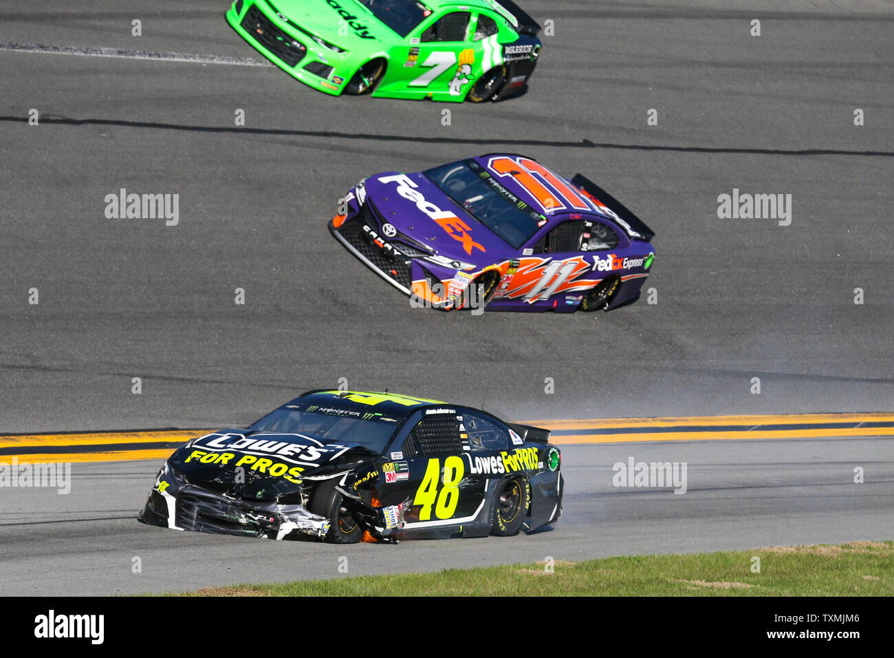 Denny Hamlin (11) and Danica Patrick (7) pass Jimmy Johnson as he limps ...
