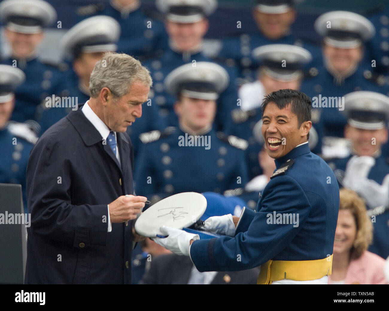 U.S. President George W. Bush (L) autographs a graduating cadet's cap ...