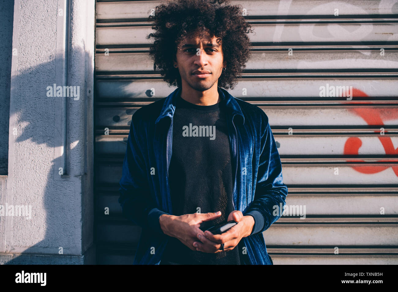 Young man waiting in front of shutters Stock Photo - Alamy