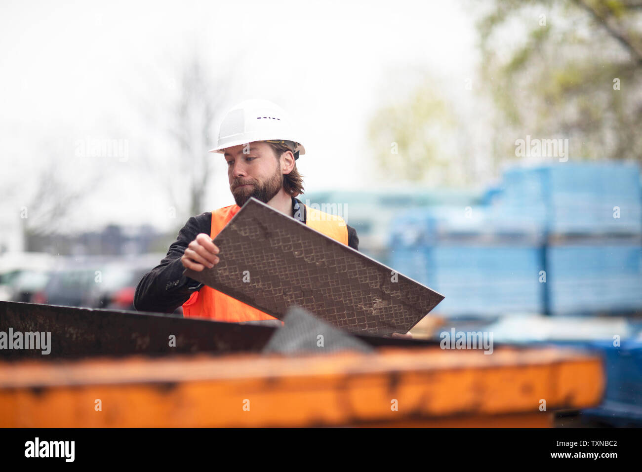 Mid adult male construction worker putting waste into waste skip Stock ...