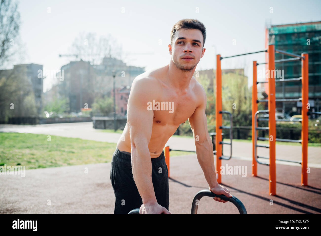 Calisthenics at outdoor gym, bare chested young man preparing to use ...