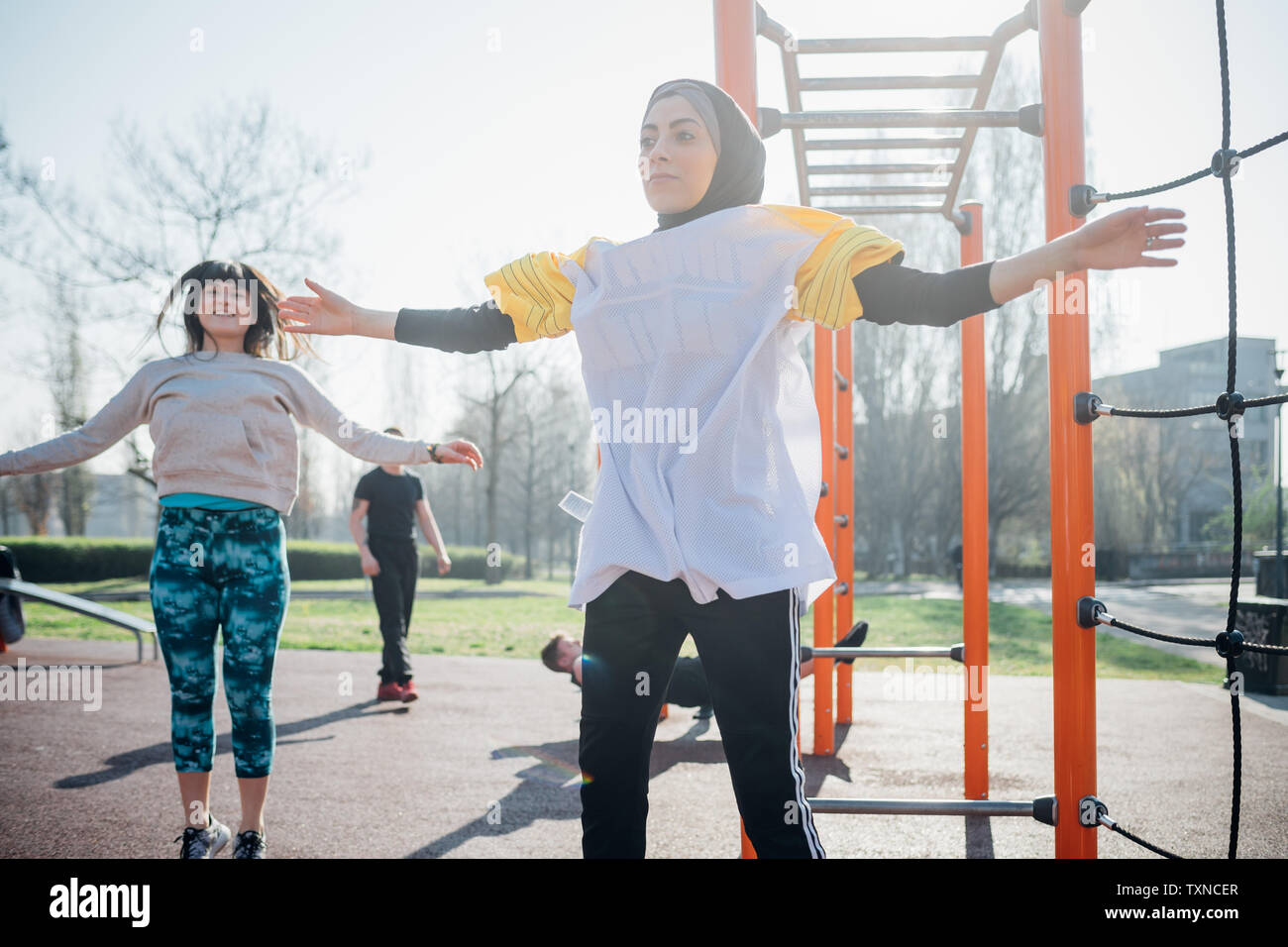 Calisthenics class at outdoor gym, young women jumping with arms ...