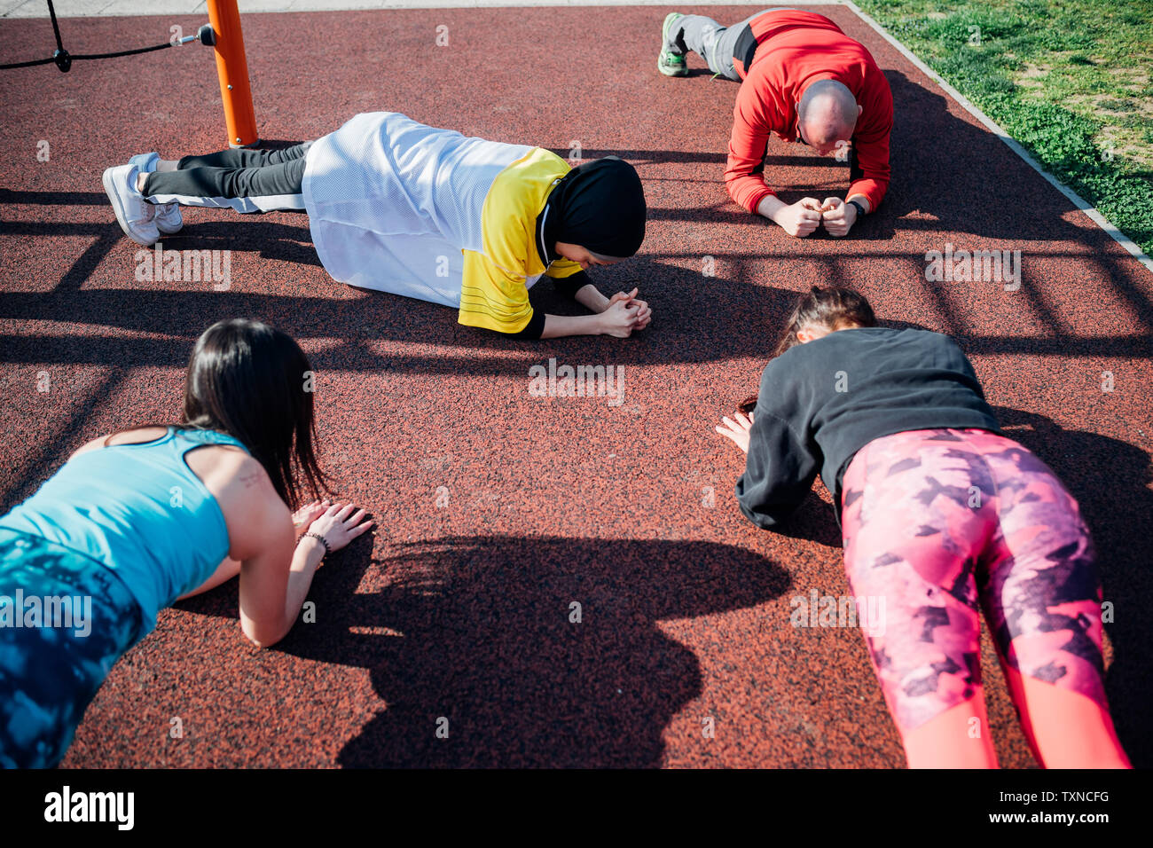 Calisthenics class at outdoor gym, young women and man practicing yoga ...