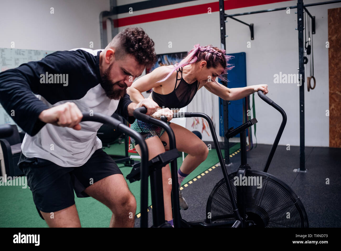 Young woman and man training together on gym exercise bikes, action ...