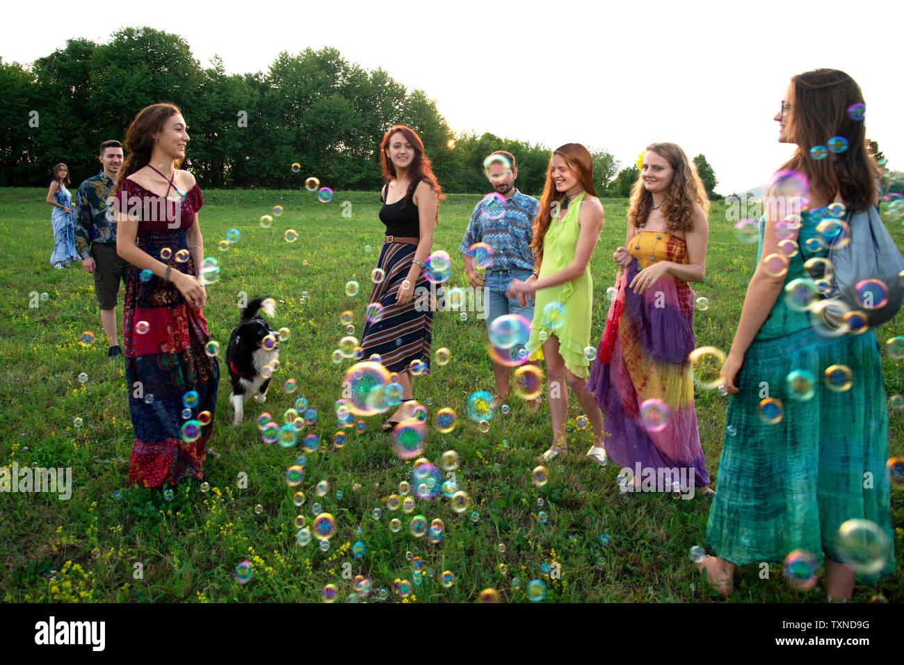 Large group of happy young adults standing in field with floating ...