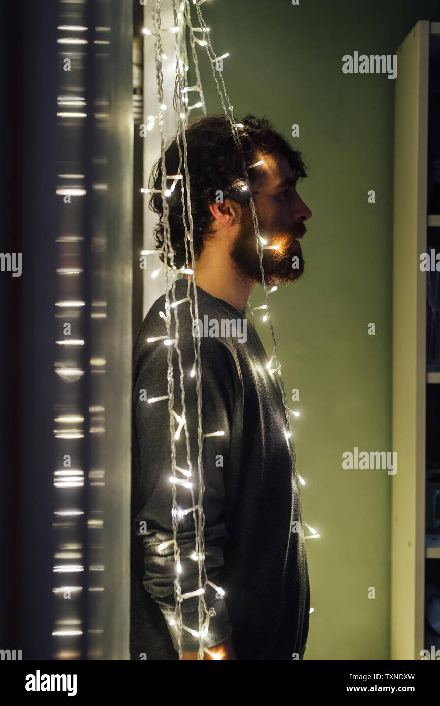Bearded young man standing between string of decorative lights Stock ...