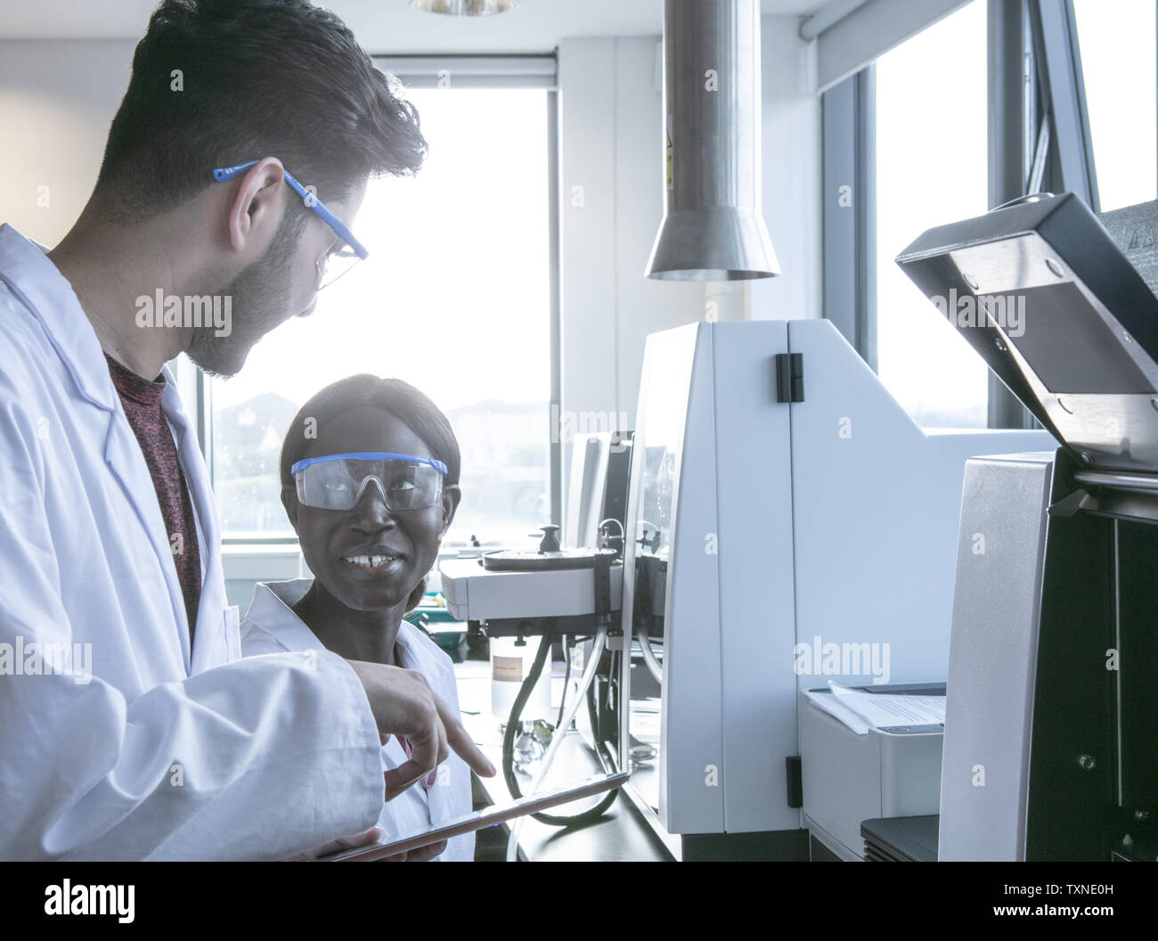 Young female and male scientists using digital tablet and having ...
