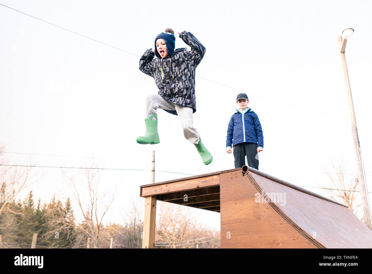 Girl watching brother jump from top of skateboard ramp Stock Photo - Alamy