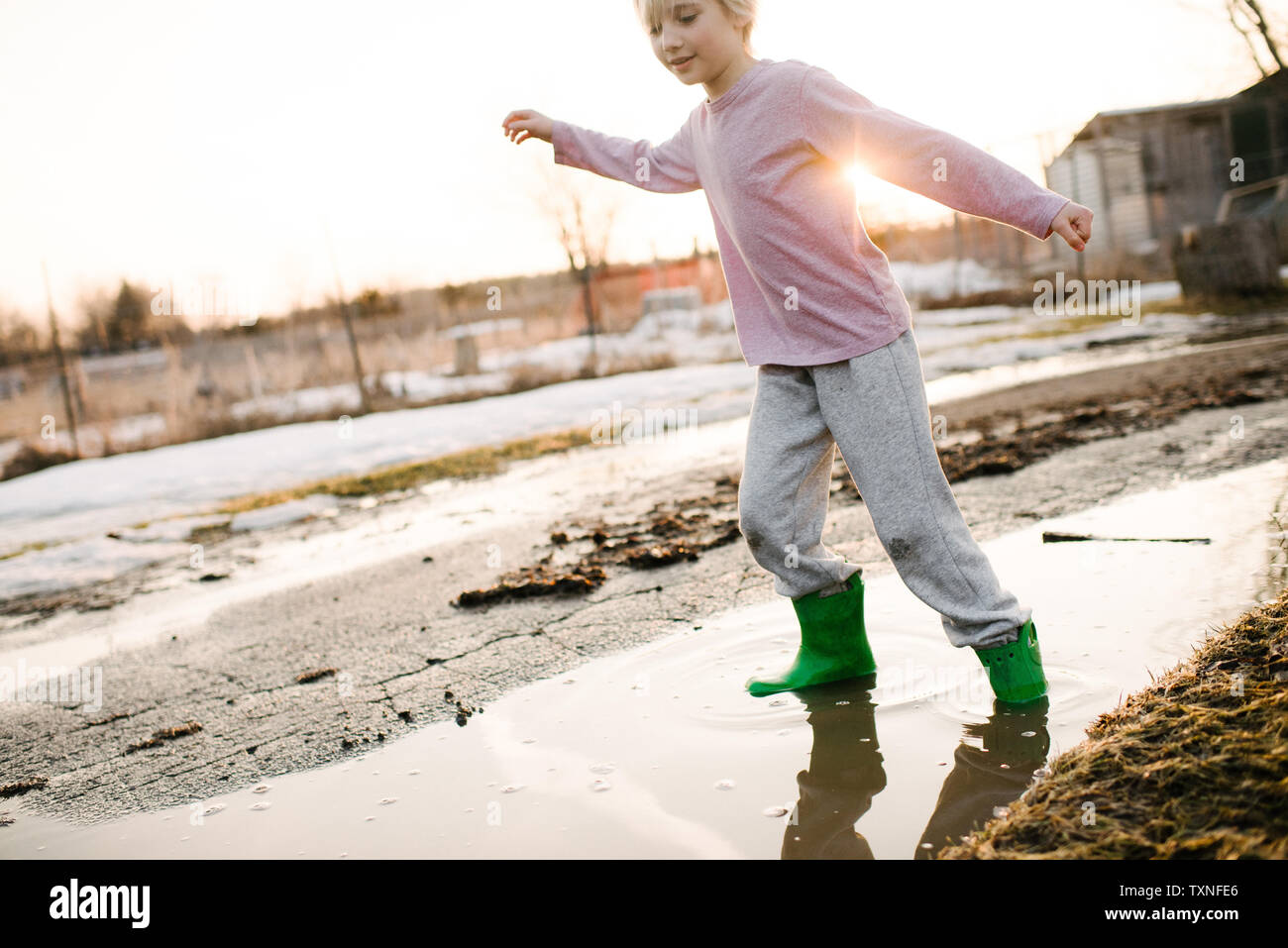 Boy playing in rural meltwater puddle Stock Photo - Alamy