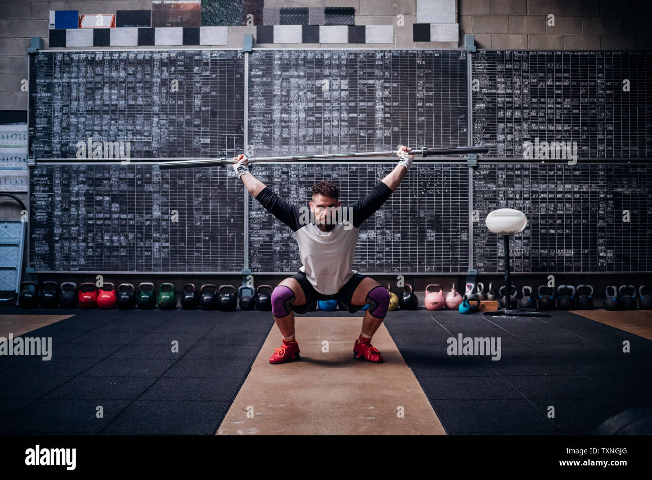 Young man lifting weight bar in gym Stock Photo - Alamy