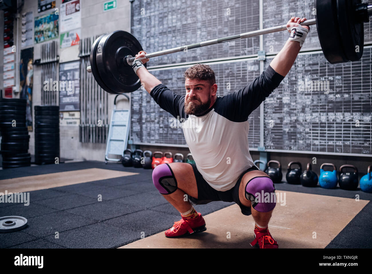Young man lifting barbell in gym Stock Photo - Alamy