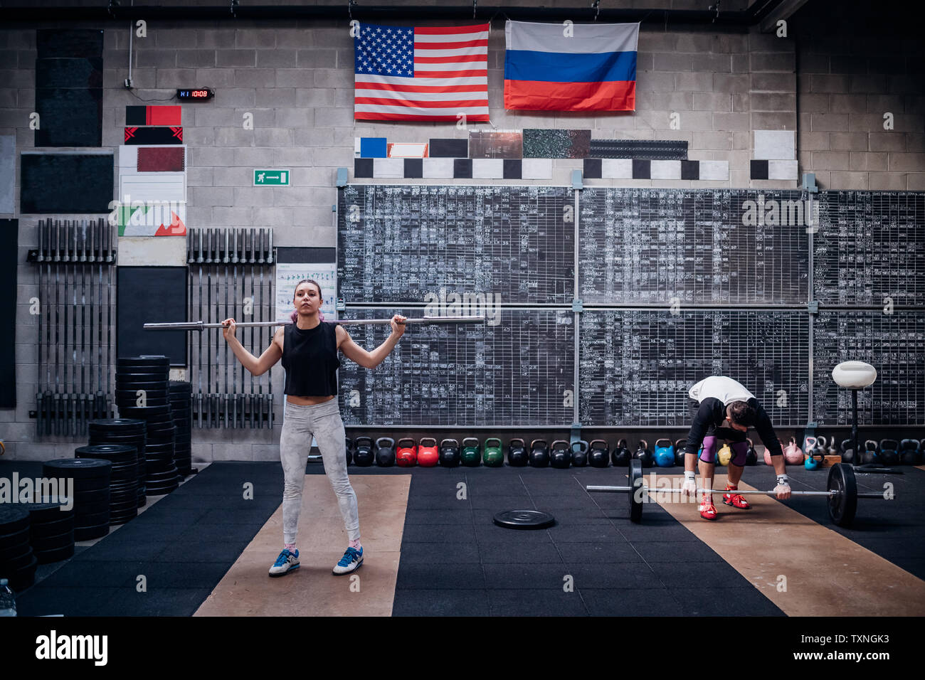 Young woman lifting weight bar in gym Stock Photo - Alamy