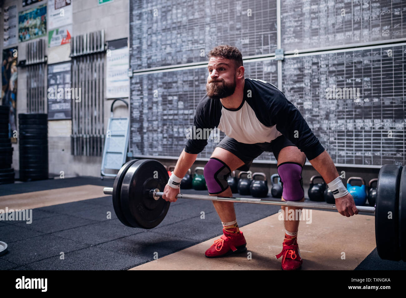 Young man lifting barbell in gym Stock Photo - Alamy