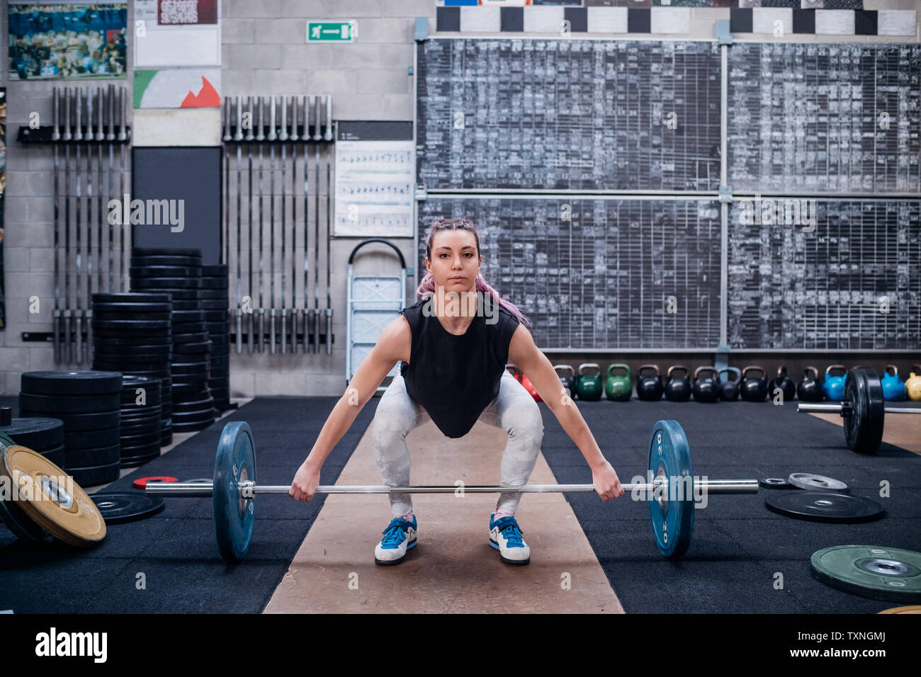 Young woman lifting barbell in gym Stock Photo - Alamy