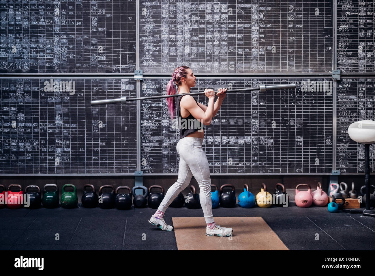 Young woman lifting weight bar in gym Stock Photo - Alamy