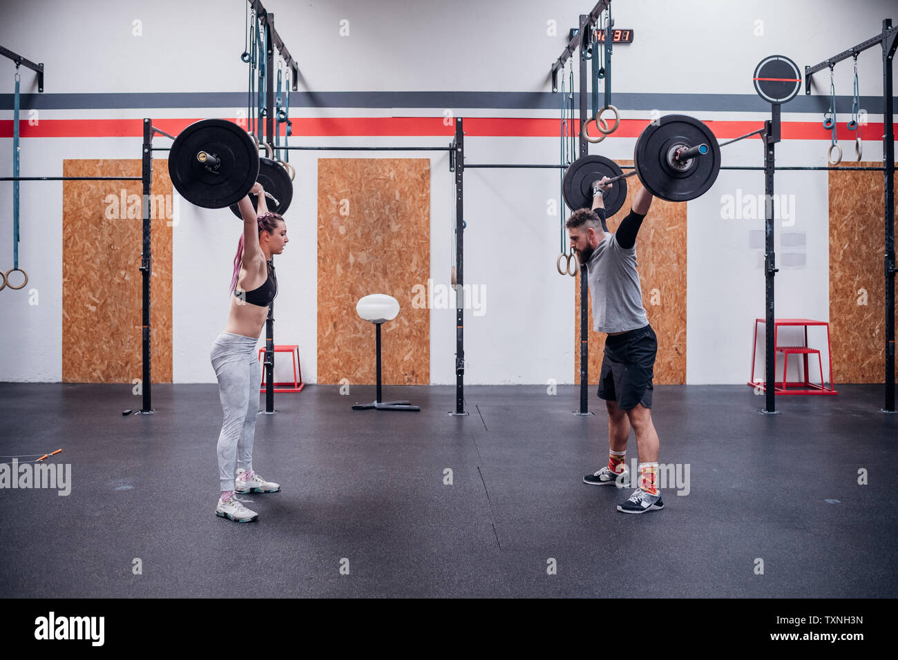 Young couple lifting barbell in gym Stock Photo - Alamy