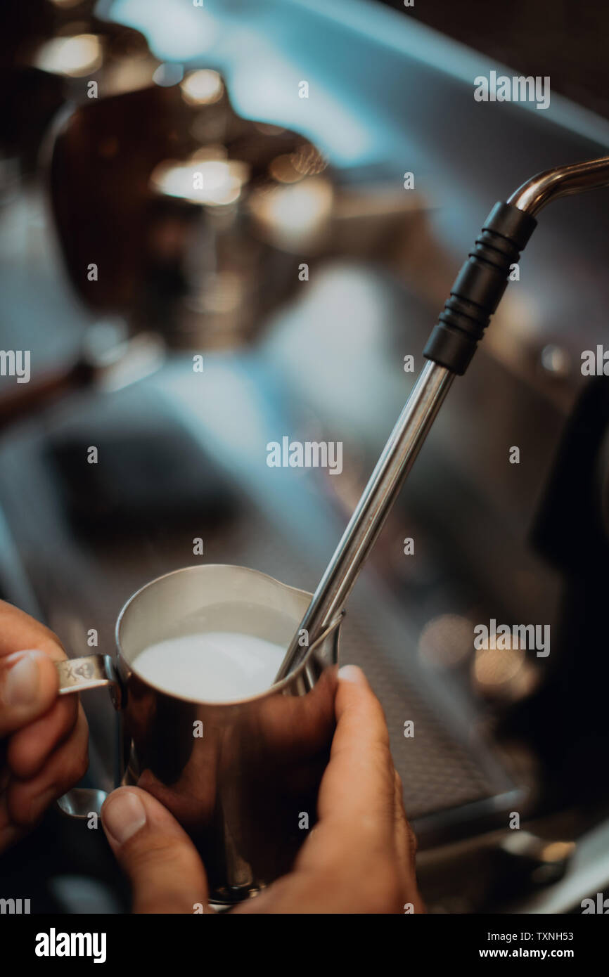 Barista heating jug of milk on coffee machine in cafe, close up of hand ...