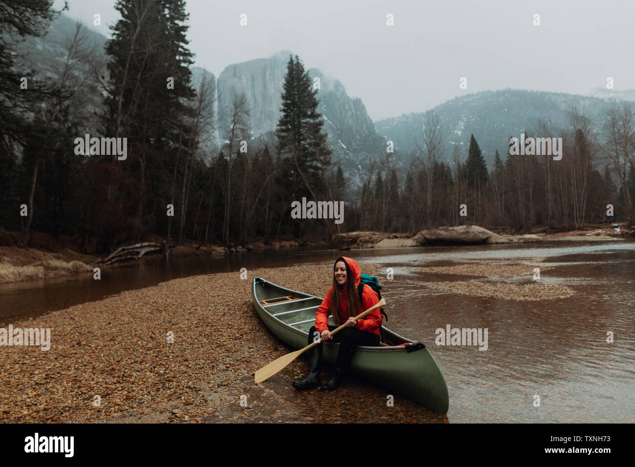 Happy young female canoeist sitting on canoe in river, Yosemite Village ...