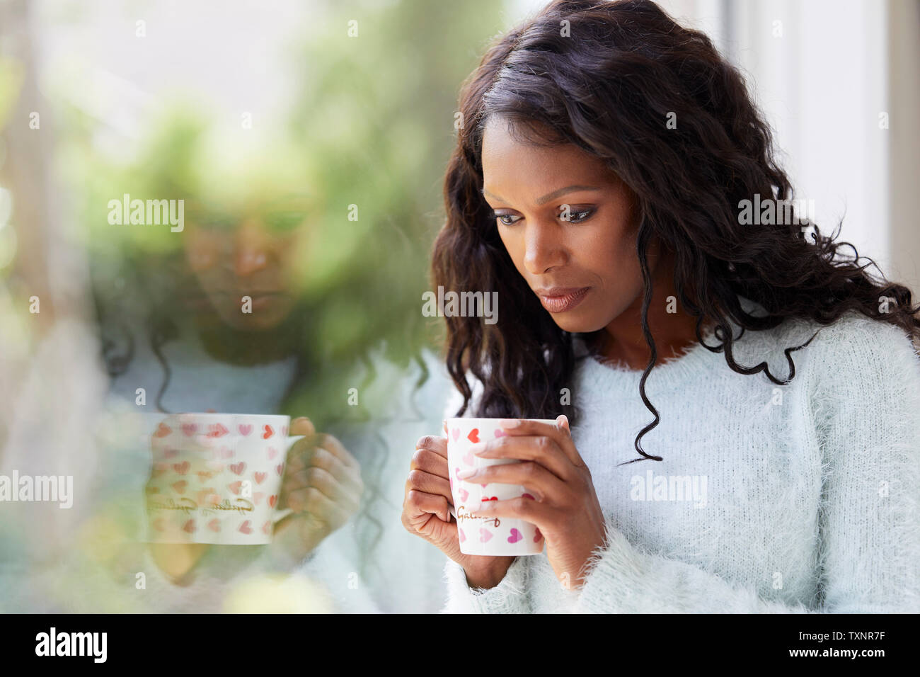 Ethnic woman looking sad sat in a window Stock Photo - Alamy