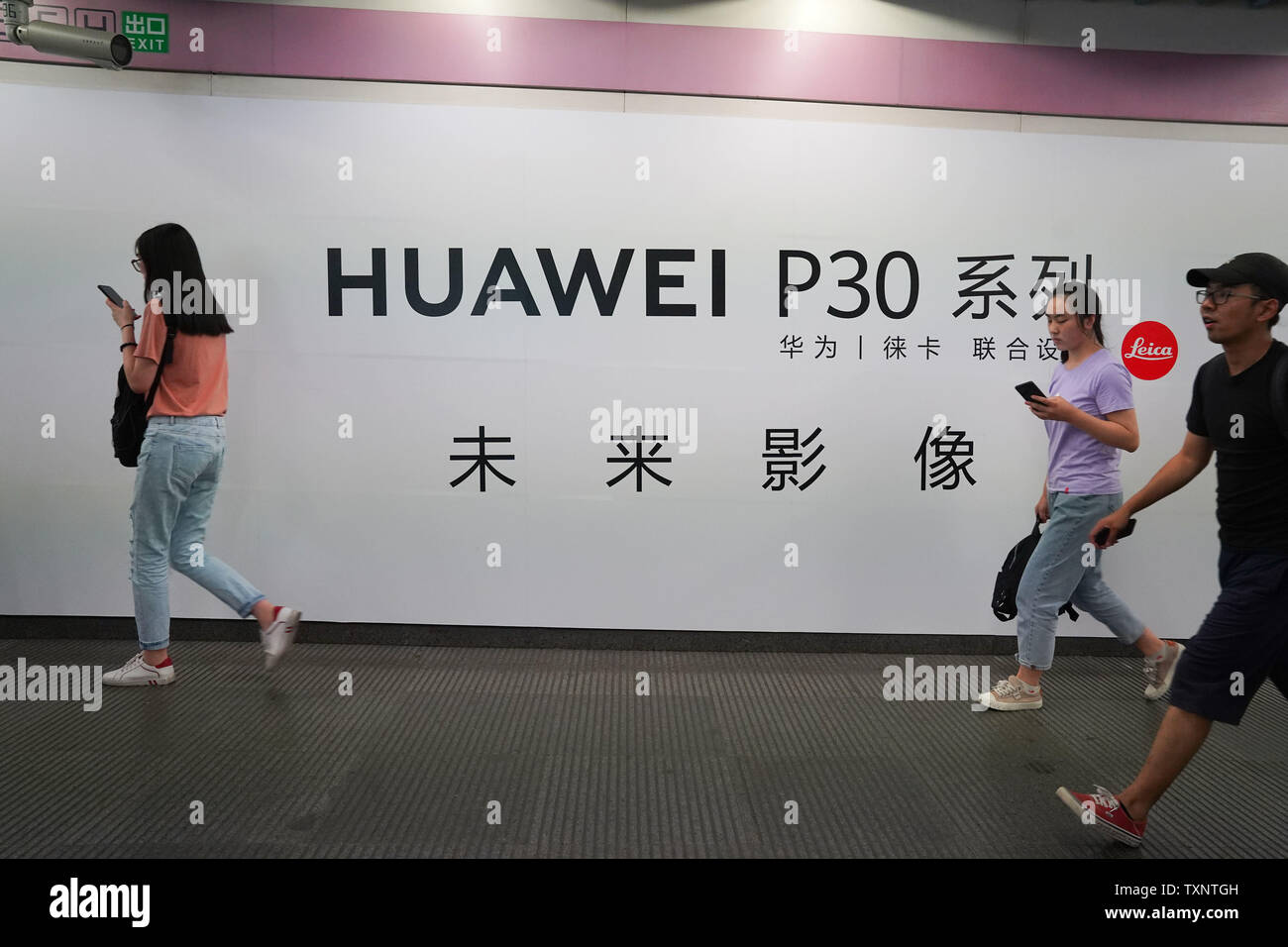 Beijing, China. 25th June, 2019. People walking past a Huawei ...