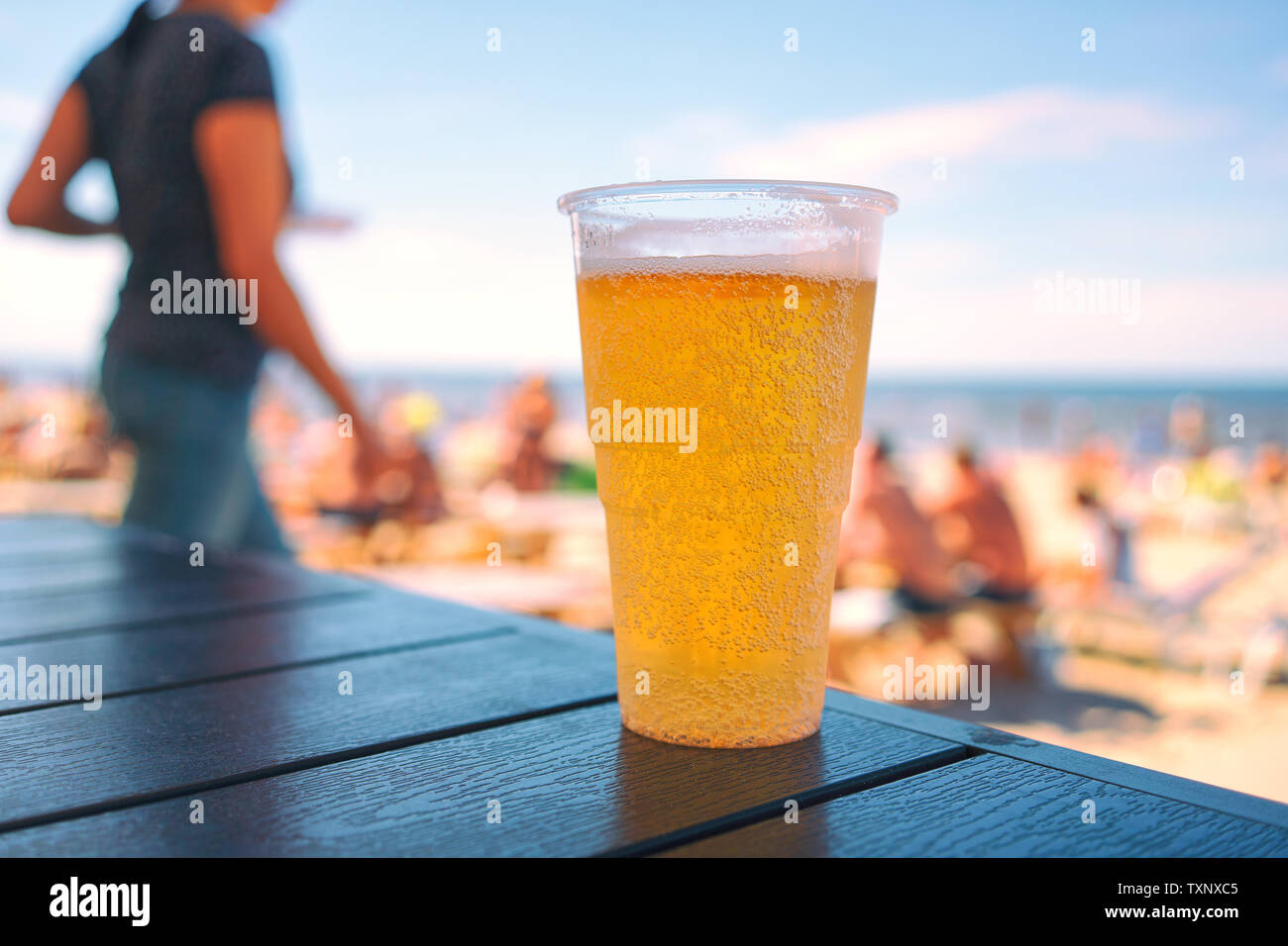A clear plastic glass of cider drink with bubbles stands on a table in ...