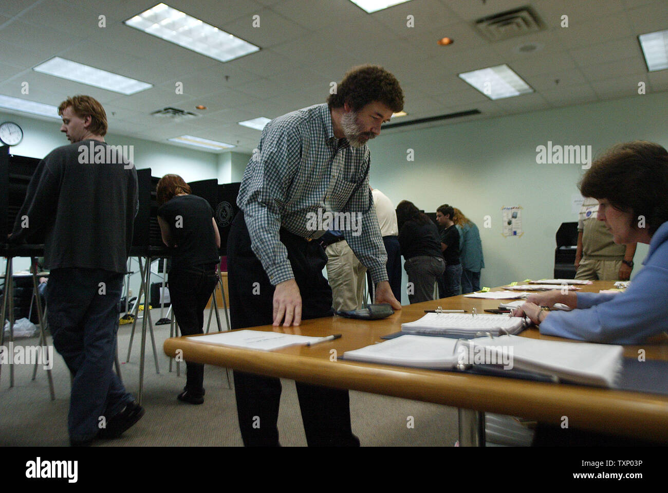 A Republican voter, left, signs in before receiving his ballot from ...