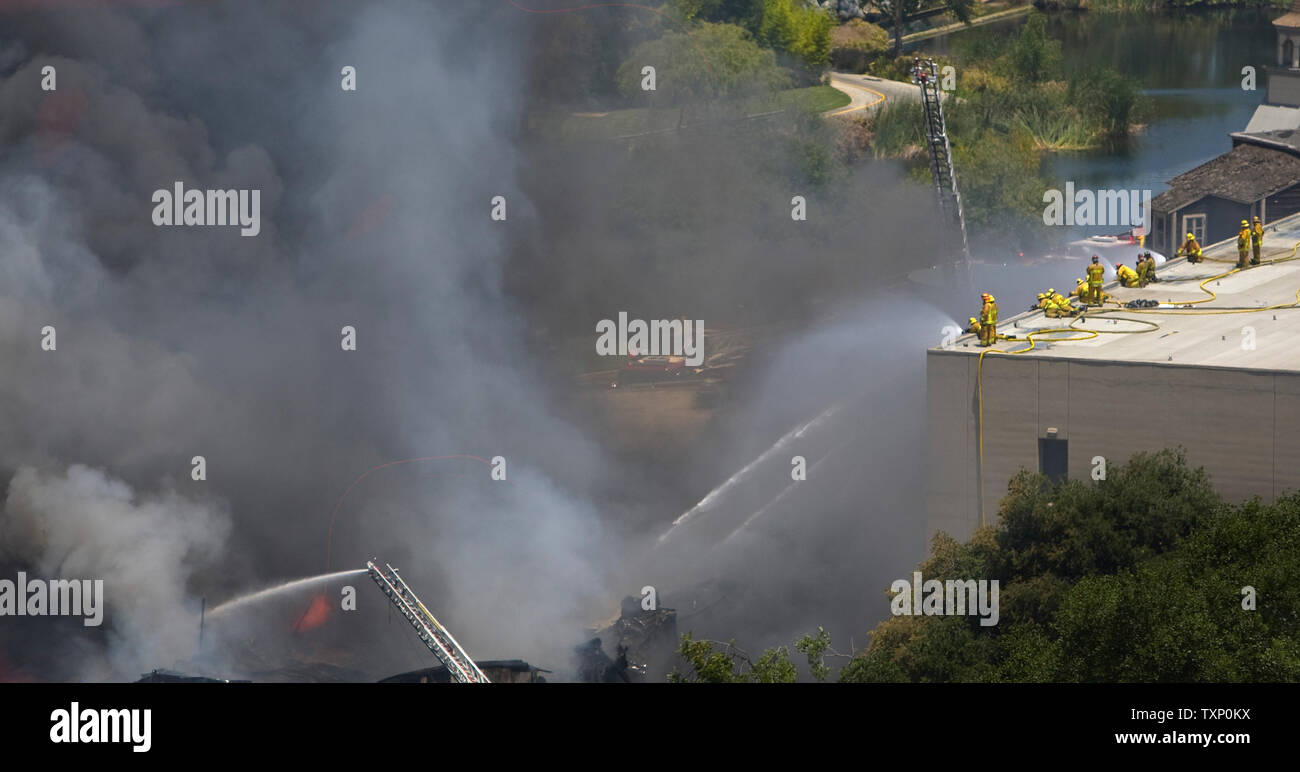 Firefighters try to extinguish the final flames of a fire that ...