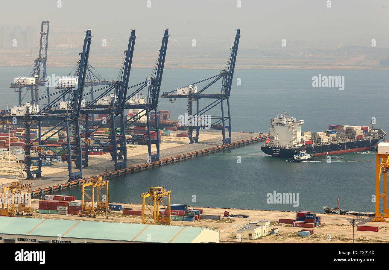 A commercial container ship leaves a row of dockside gantry cranes in ...