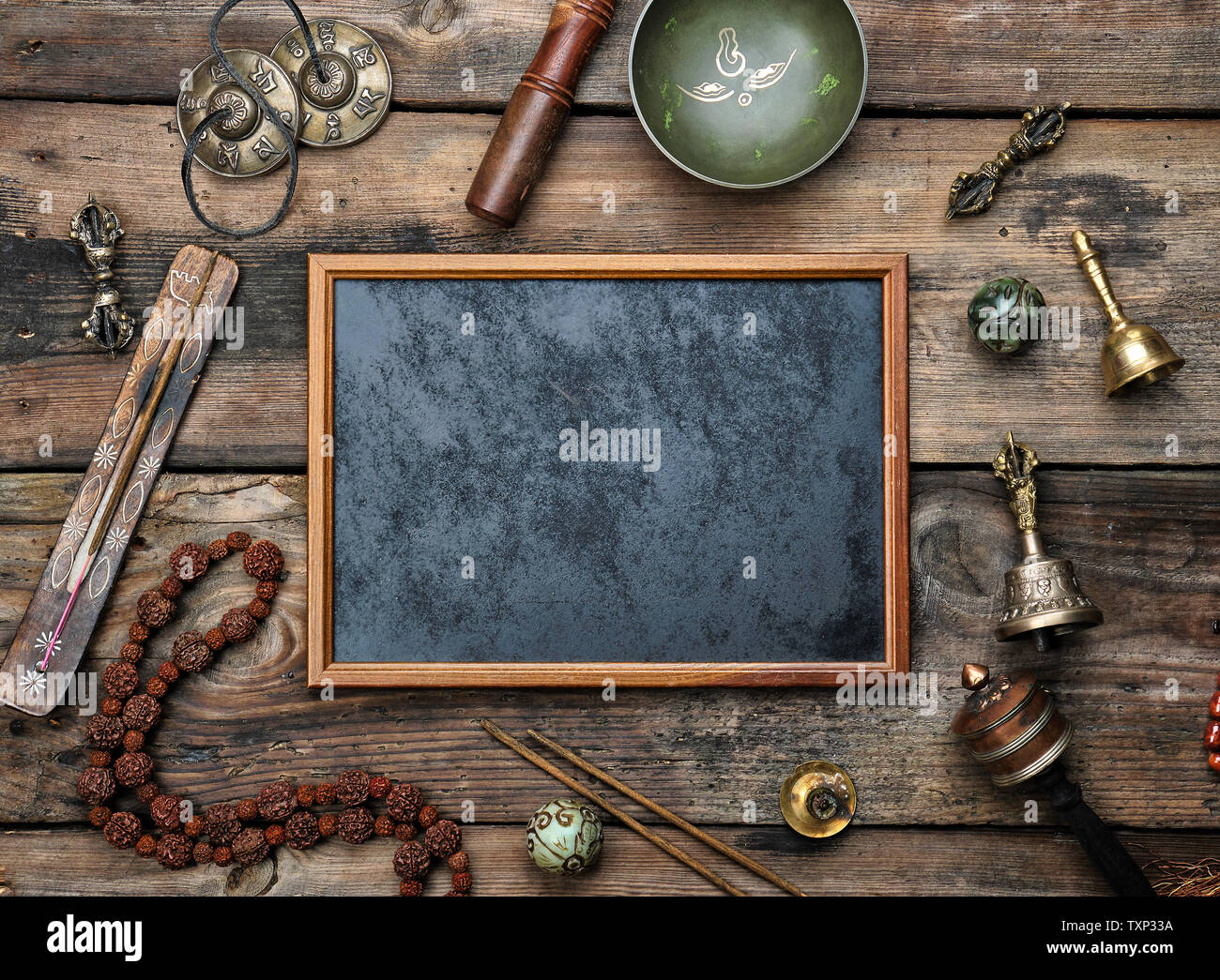 Empty wooden frame and copper singing bowl, prayer beads, prayer drum ...