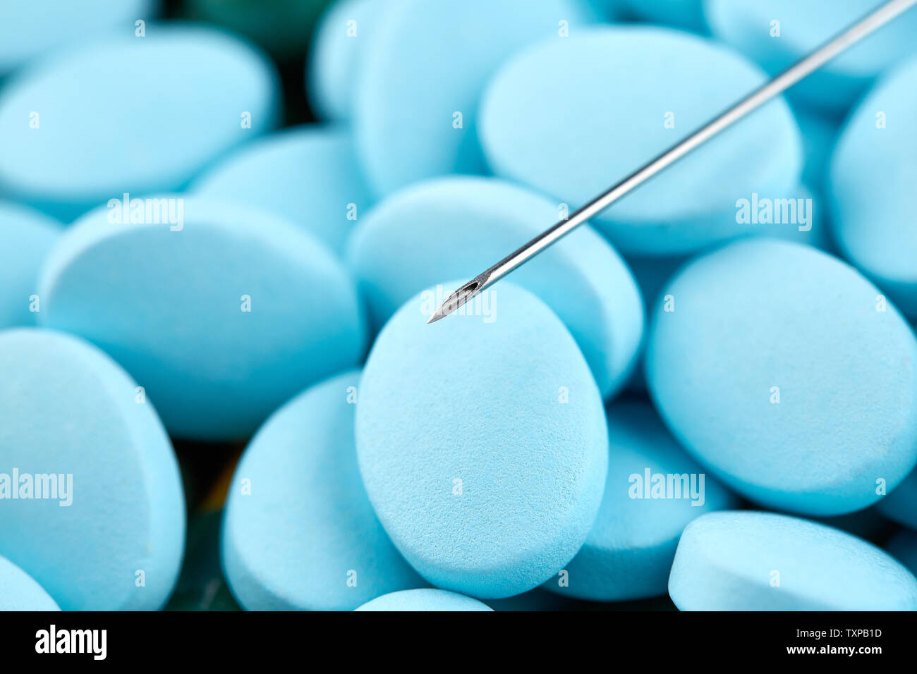 Macro photo of syringe needle and many blue pills Stock Photo - Alamy