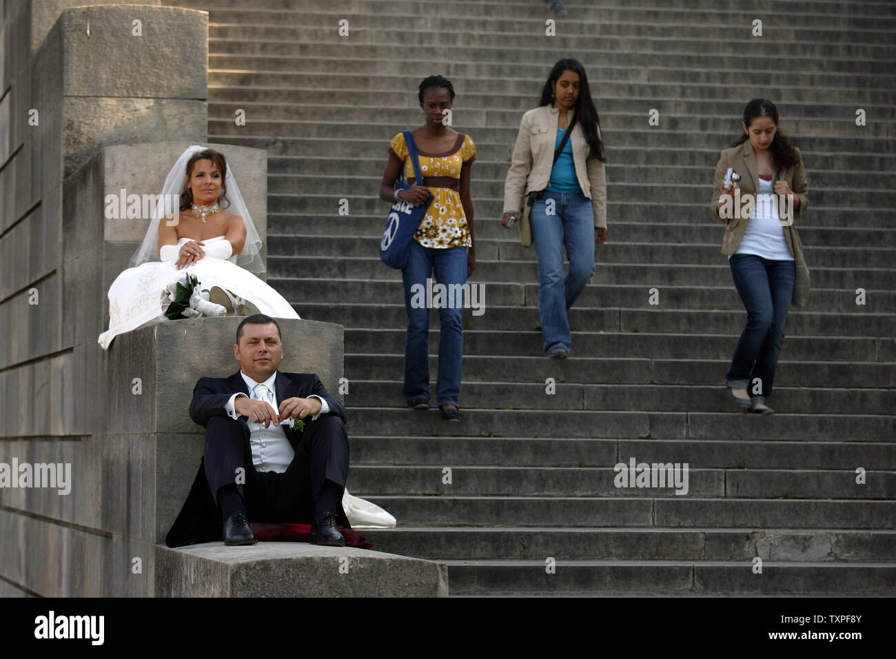 A bride and a groom pose for a photograph next to the Eiffel tower, the ...