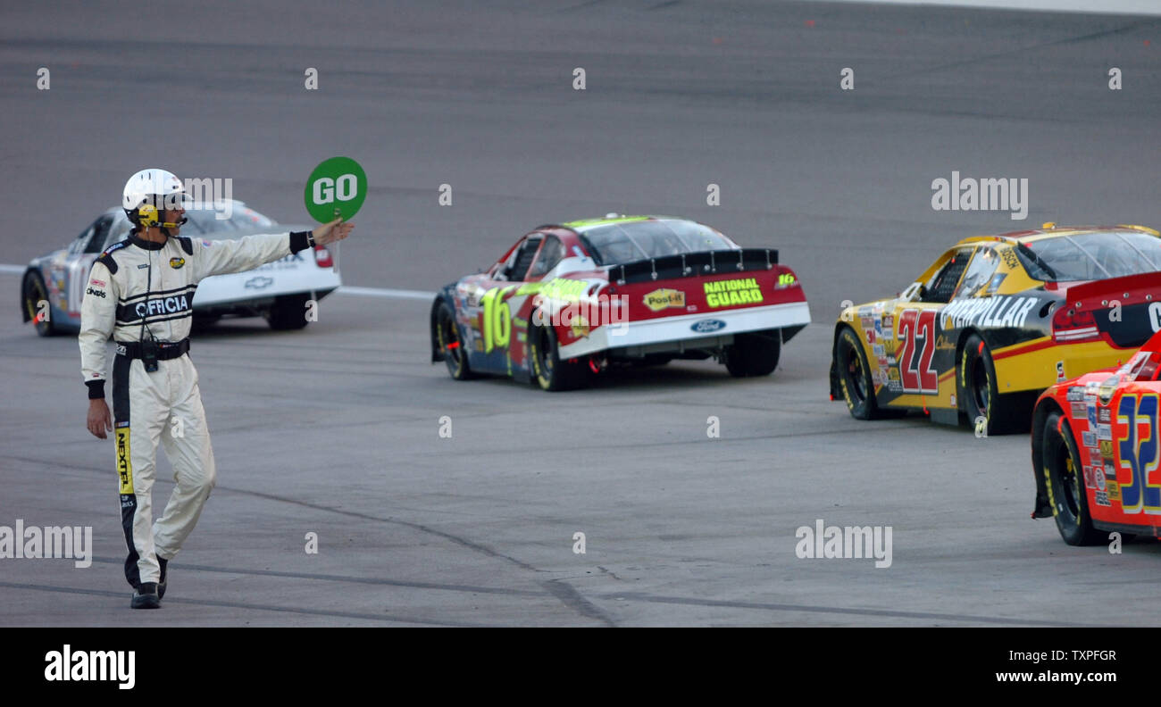 A NASCAR official give drivers the "go" sign as they leave pit row ...