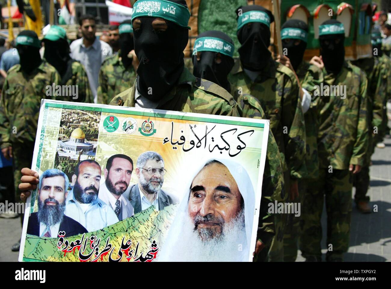 Palestinian masked militants from the Islamic Hamas hold a poster of ...