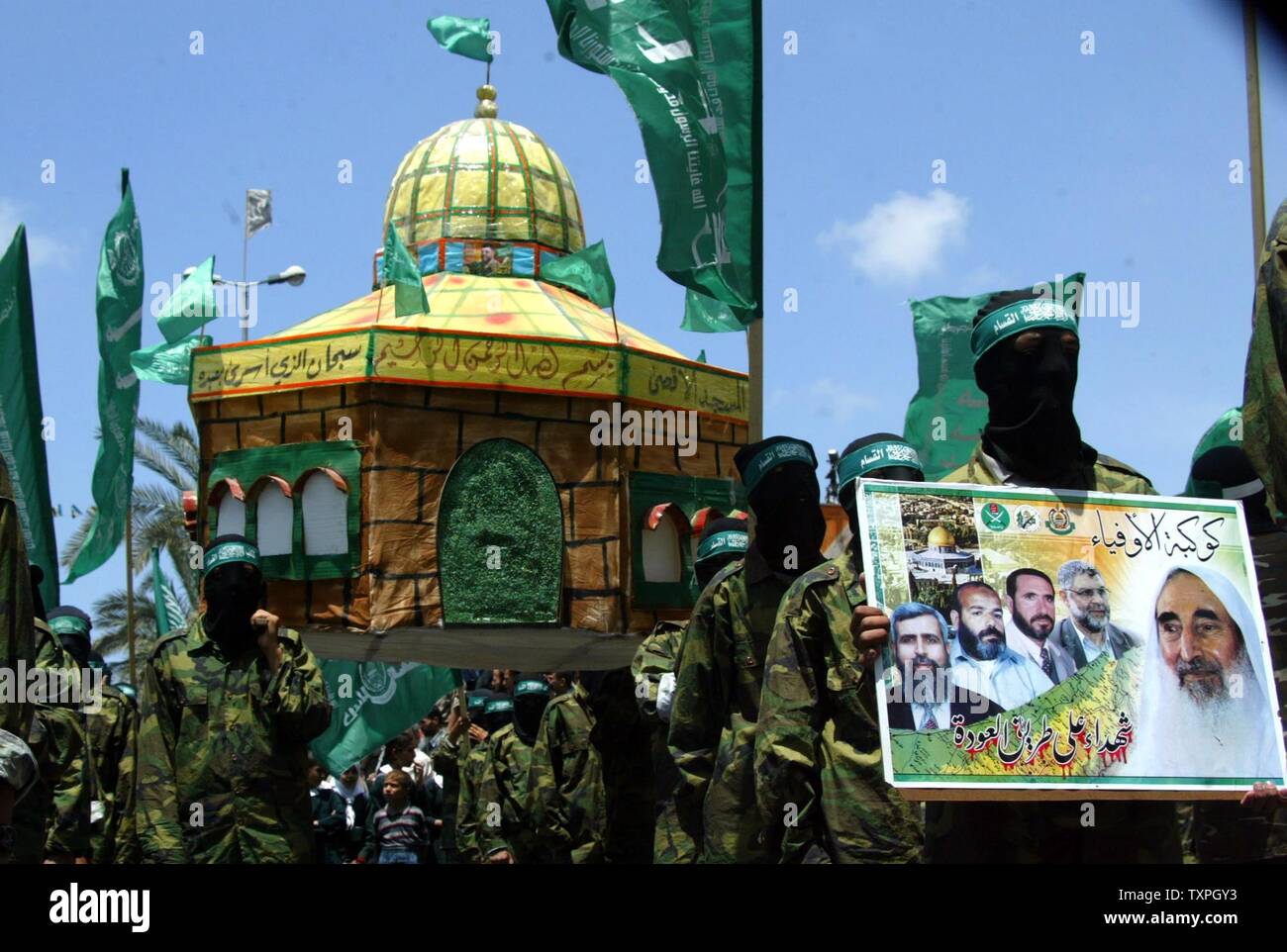 Palestinian masked militants from the Islamic Hamas hold a poster of ...
