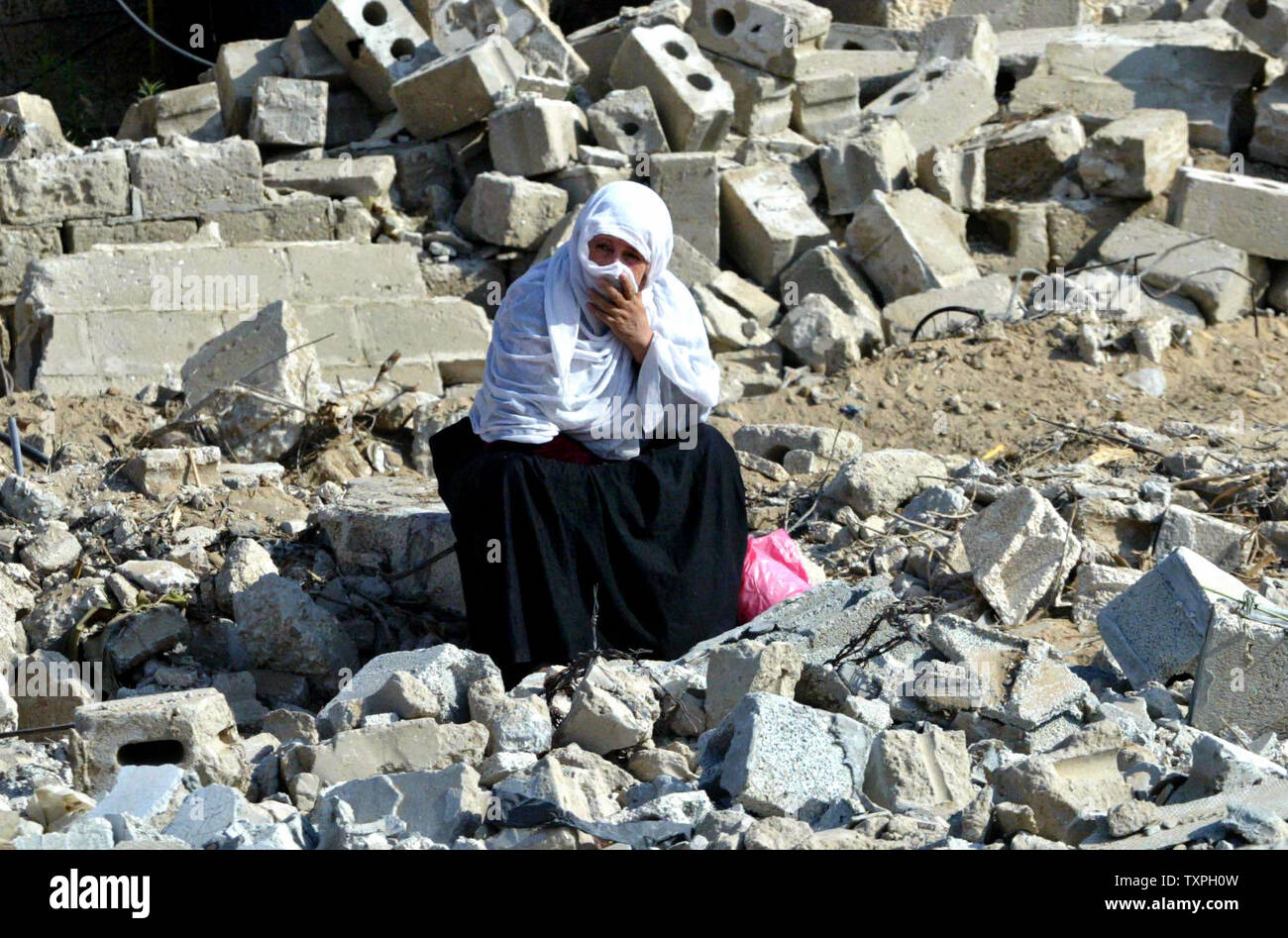 A Palestinian woman sits on front of a destroyed house, after Israeli ...
