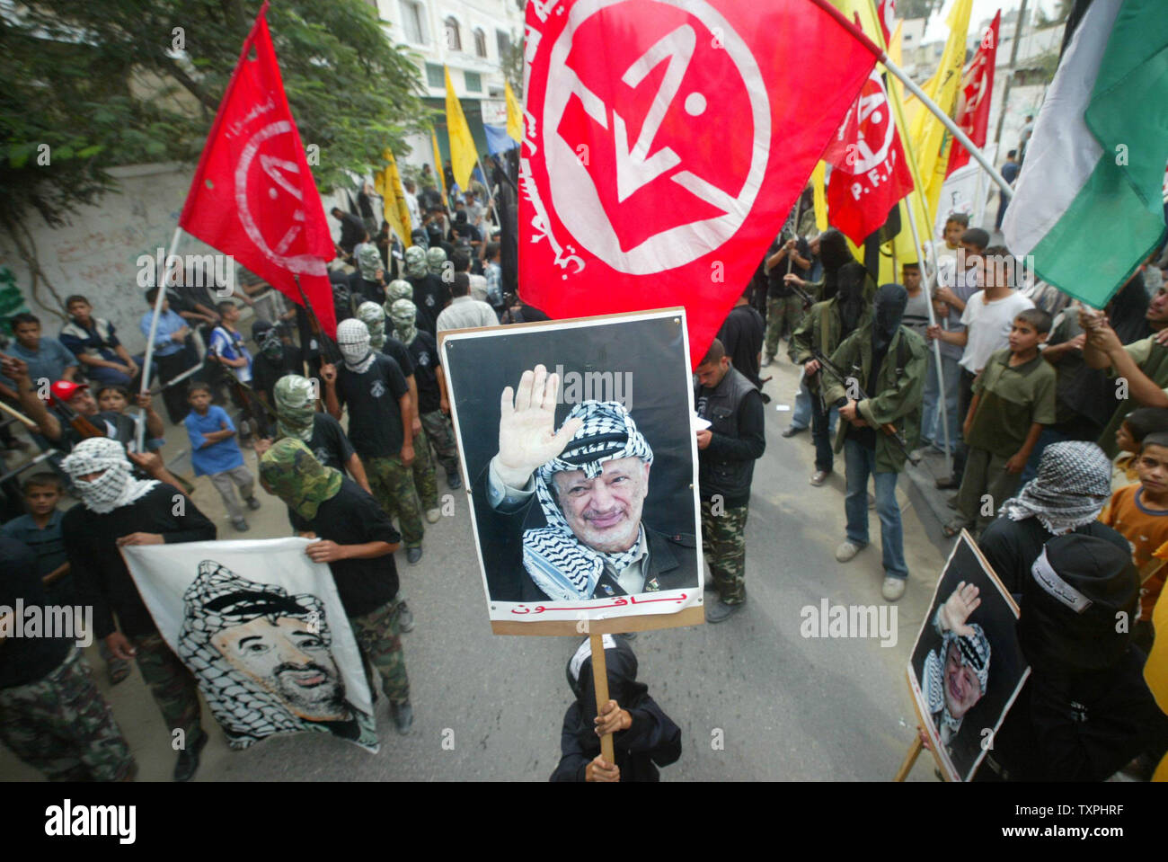 Masked Palestinian militants march with posters of the late President ...