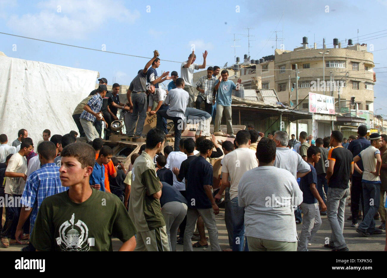 Palestinian boys throw stones as a Palestinian police armoured ...