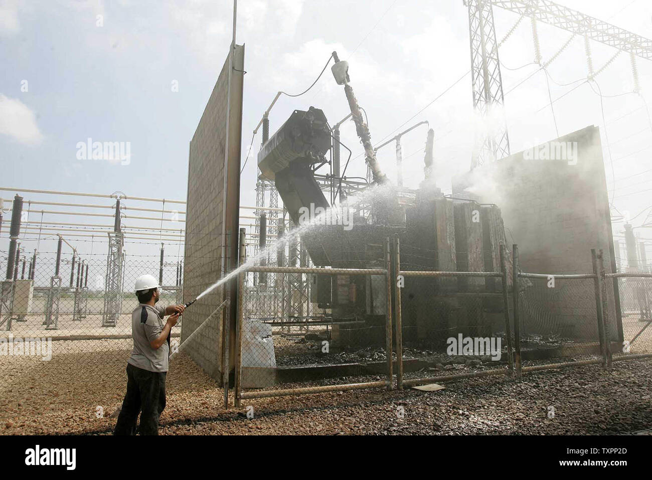 A Palestinian electricity worker extinguishes a fire inside the ...