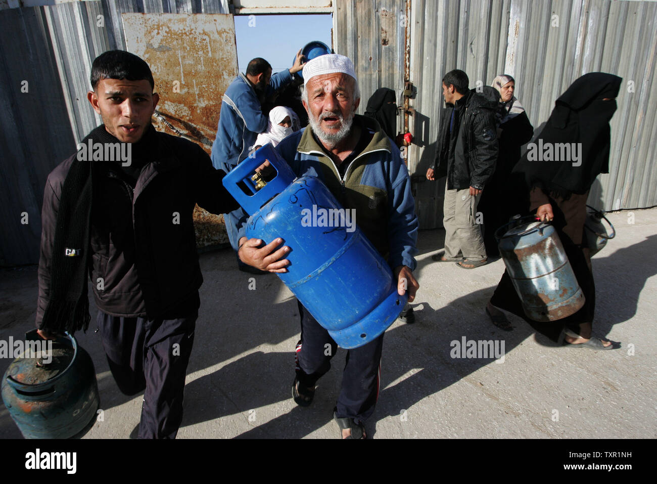 Palestinians carries empty gas canisters ran to inside of a fuel ...