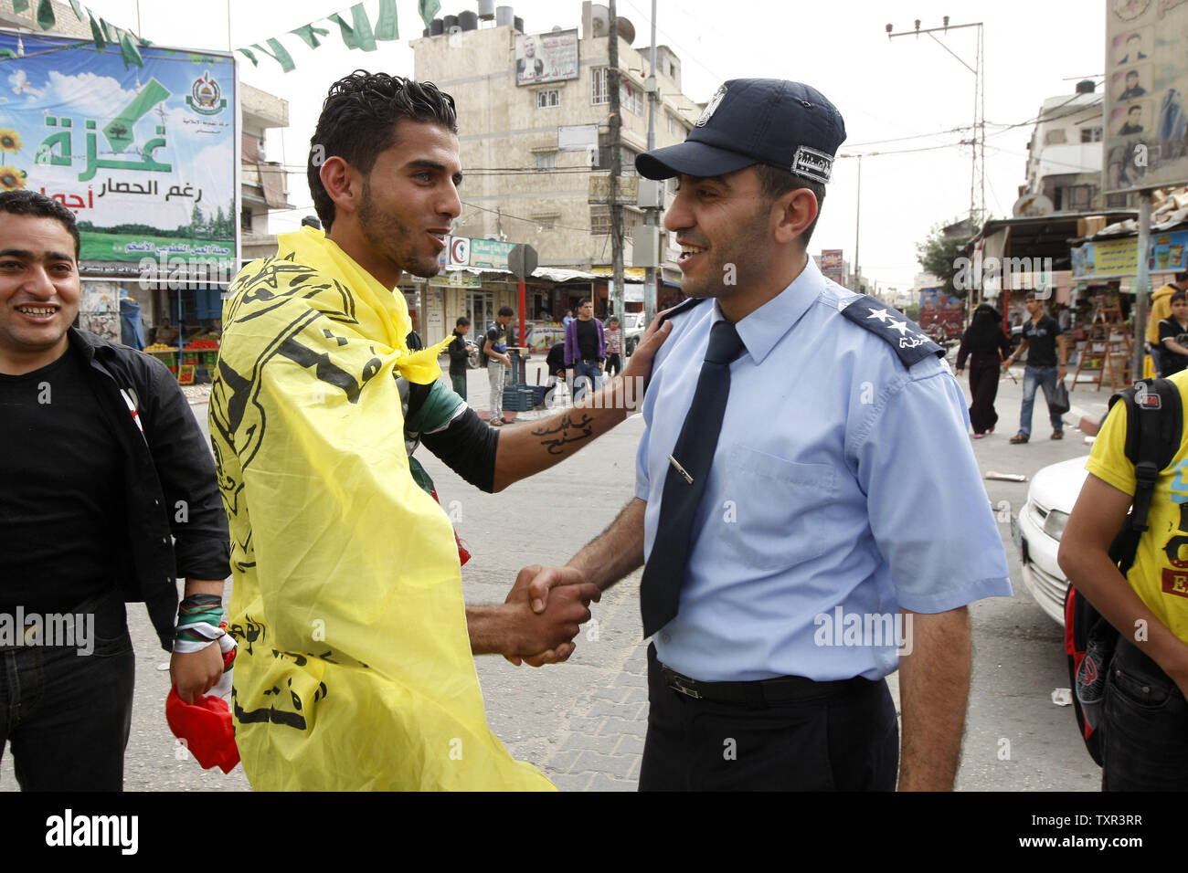 A Palestinian man wrapped with the Fatah party flag shakes hands with a ...