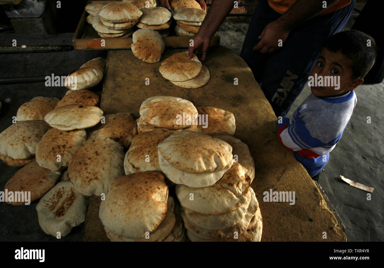 A Palestinian baker prepares pita bread in a wood burning stove at a ...
