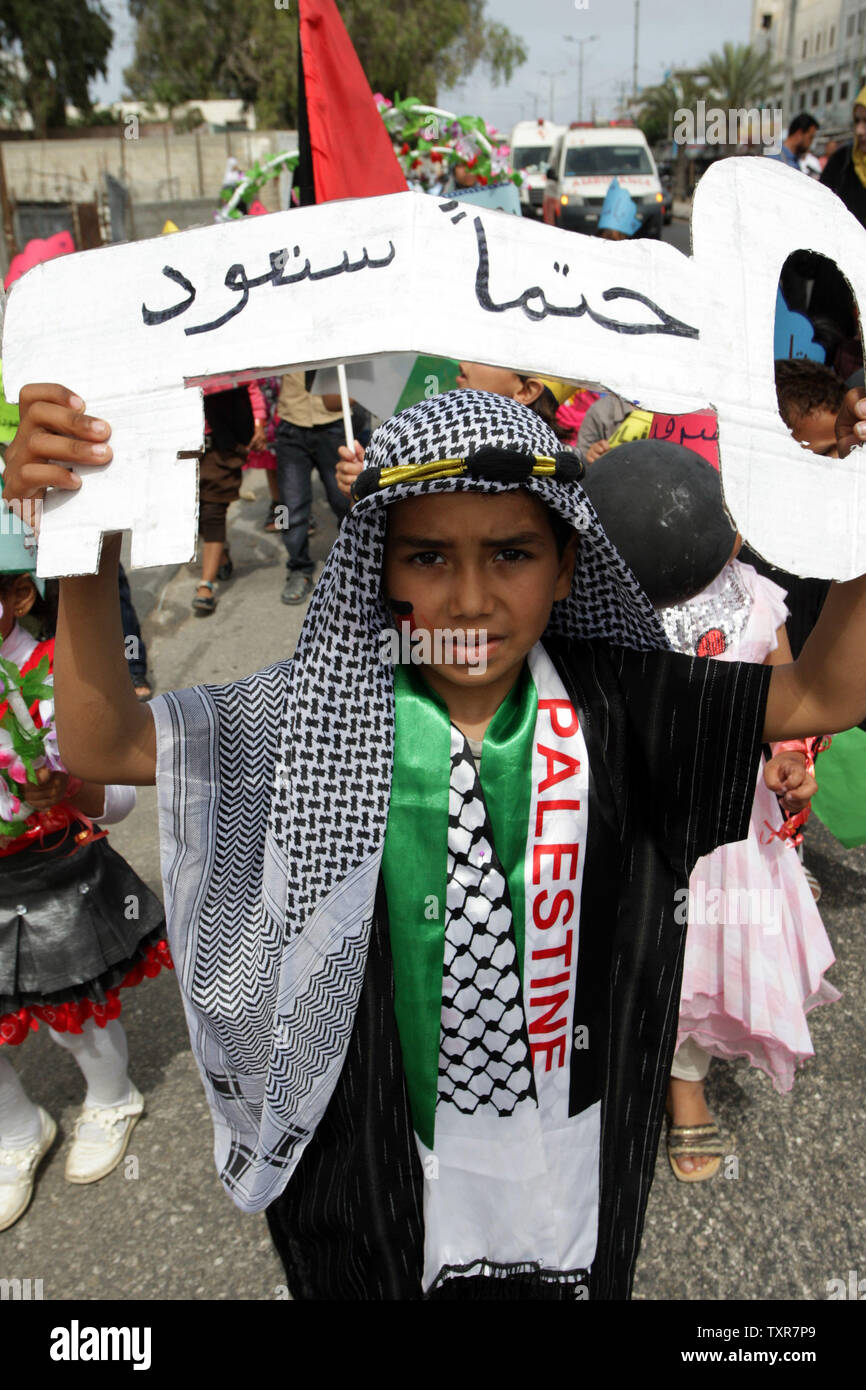 A Palestinian child, wearing a traditional Arab headdress, holds a key ...