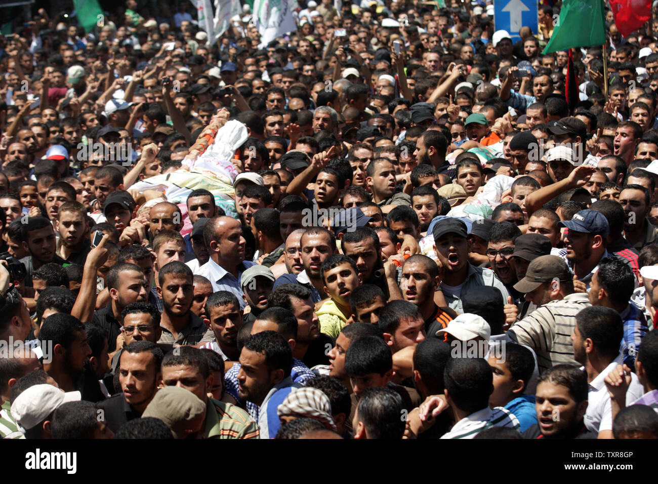 Palestinians carry the bodies of three senior Hamas commanders, who ...