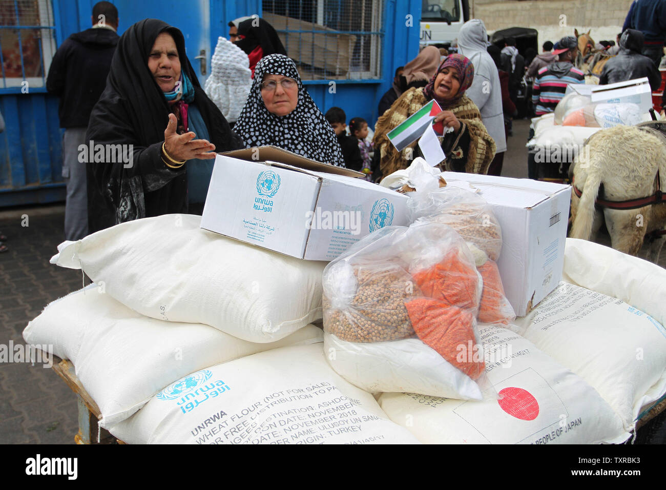 Palestinian refugees collect aid parcels at a United Nations food ...