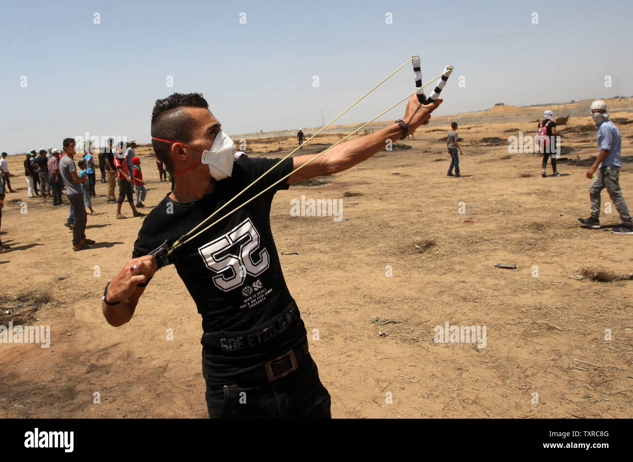 A Palestinian youth uses a slingshot to hurl stones during a protest ...
