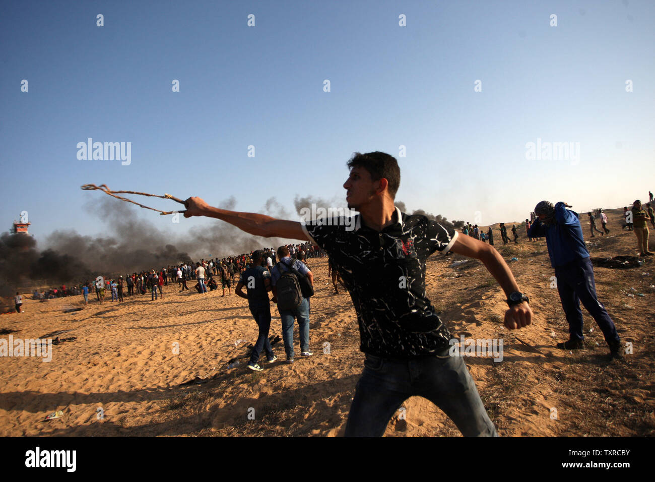 A Palestinian youth uses a slingshot to hurl stones during of clashes ...