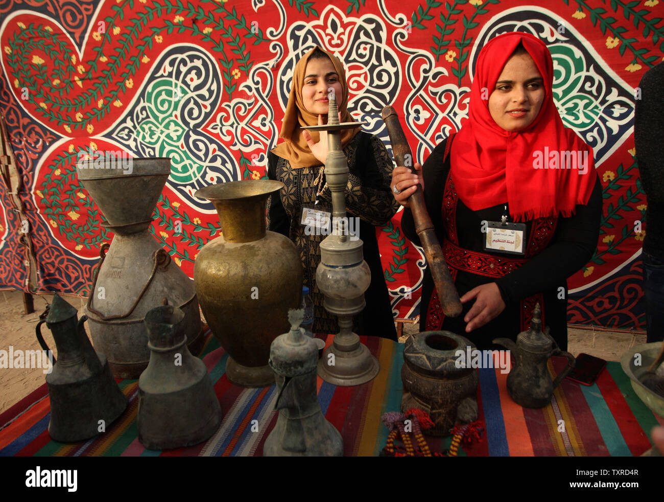 Palestinian women wear traditional clothing and display old tools at an ...