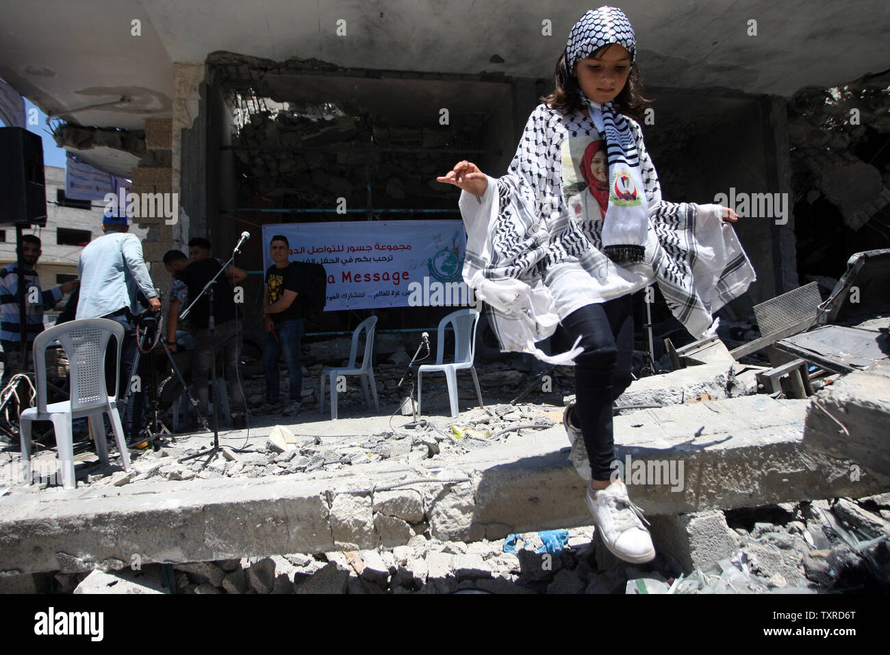 A Palestinian girl walks on the rubble of a building as members of the ...